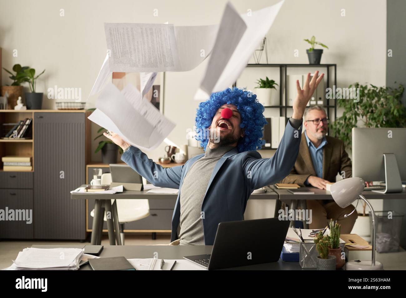 Young ecstatic clown male economist throwing financial paper documents ...
