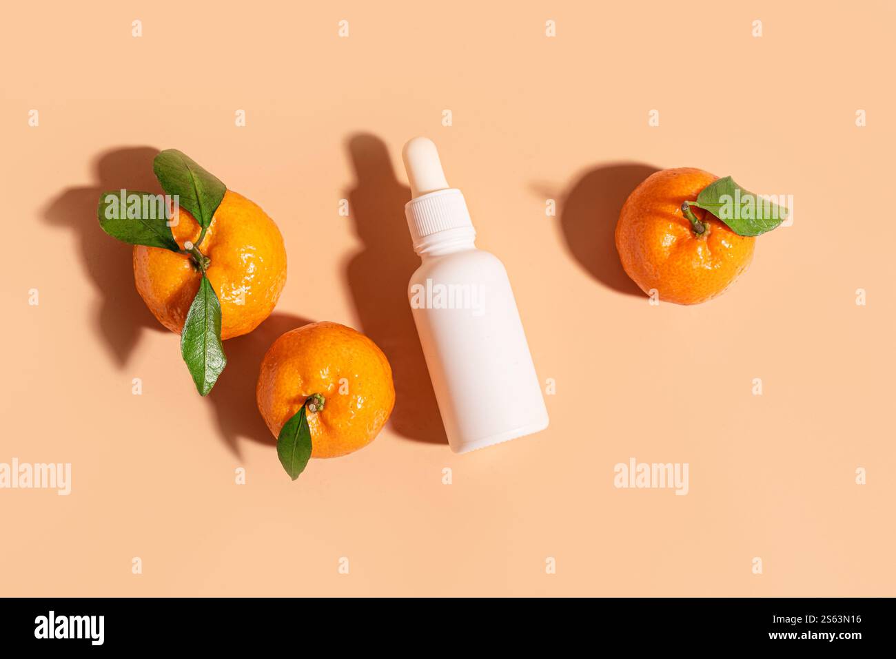 White unlabeled cosmetic serum and orange citrus fruit, top view ...
