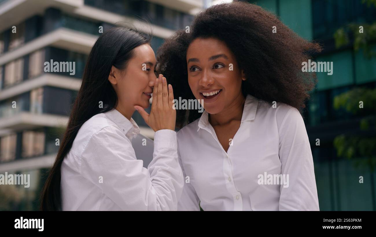Asian Korean Chinese African American women businesswomen whisper secret gossip laughter ...
