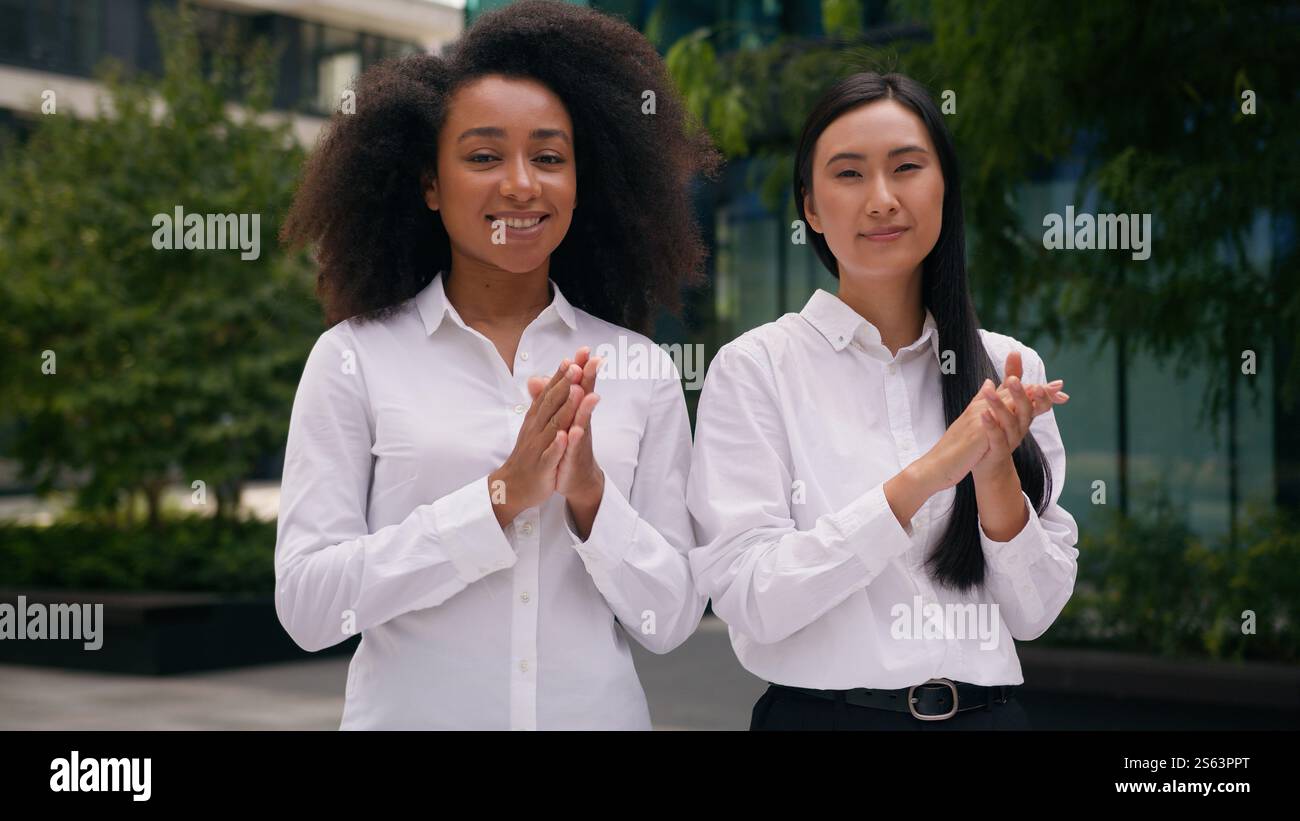 Two Asian Korean Chinese African American women businesswomen applause cheering clapping ...