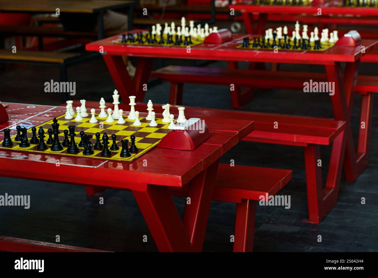 Bright red tables showcase chess sets waiting for players to engage in ...
