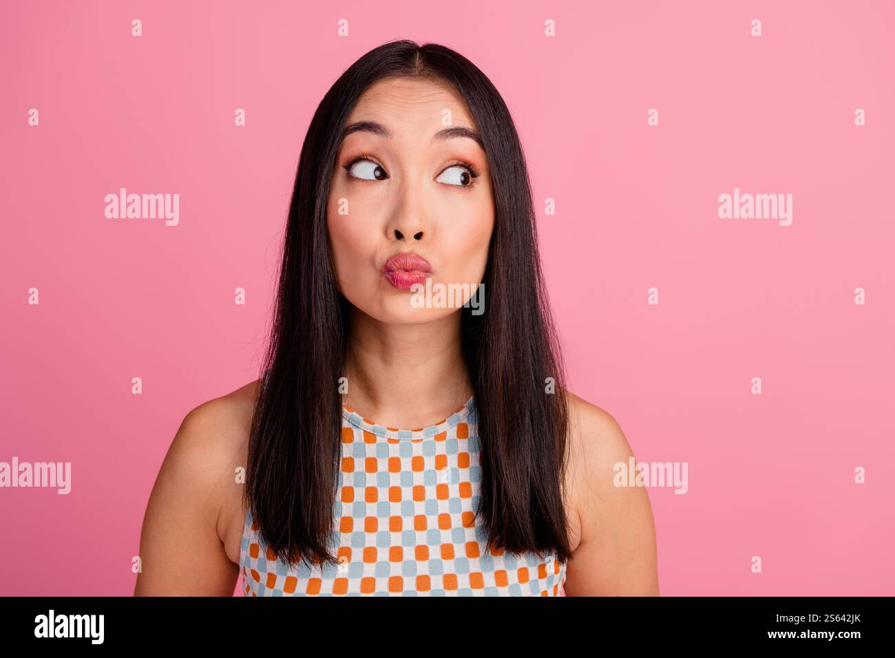 Young asian woman with playful expression looks to the side, posing ...