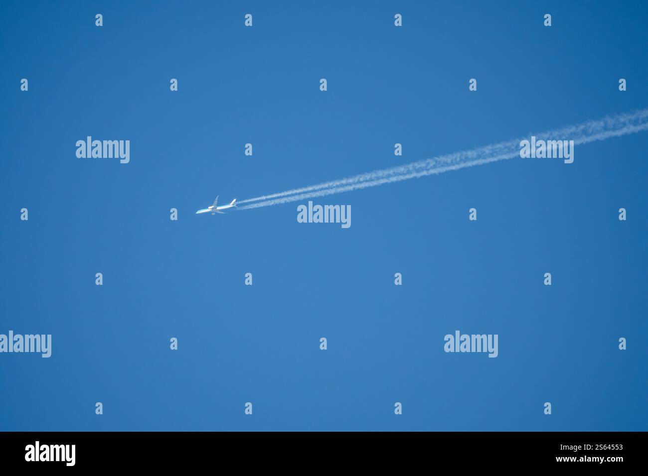 twin engined jet liner aircraft in deep blue sky with vapour (contrails ...