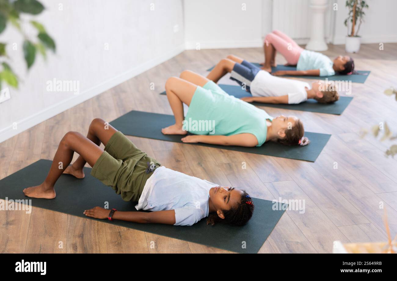 Girls and boys doing abdominal crunches with outstretched arms to ...