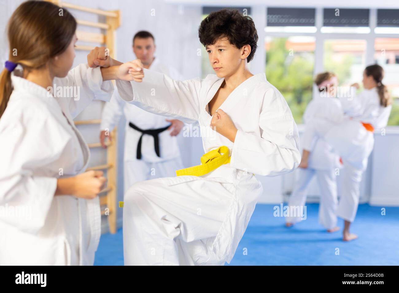 Teenagers girl and boy in kimono sparring together in gym during karate ...