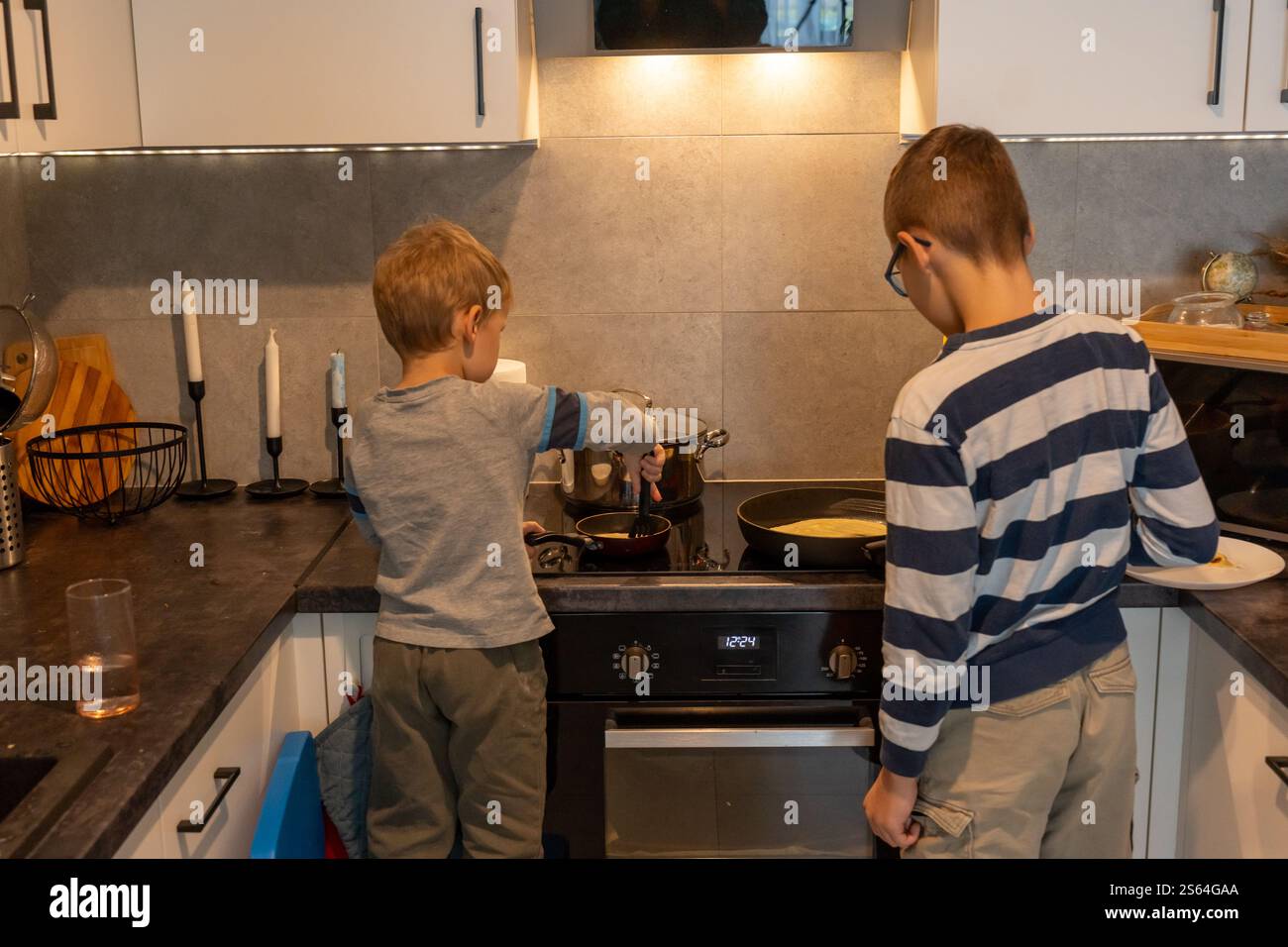Two boys cook together in modern kitchen, emphasizing teamwork and ...