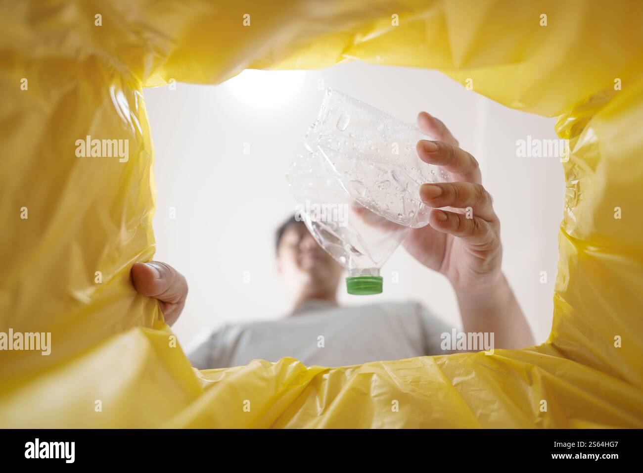 Image from inside yellow recycling bag of man throwing empty plastic ...