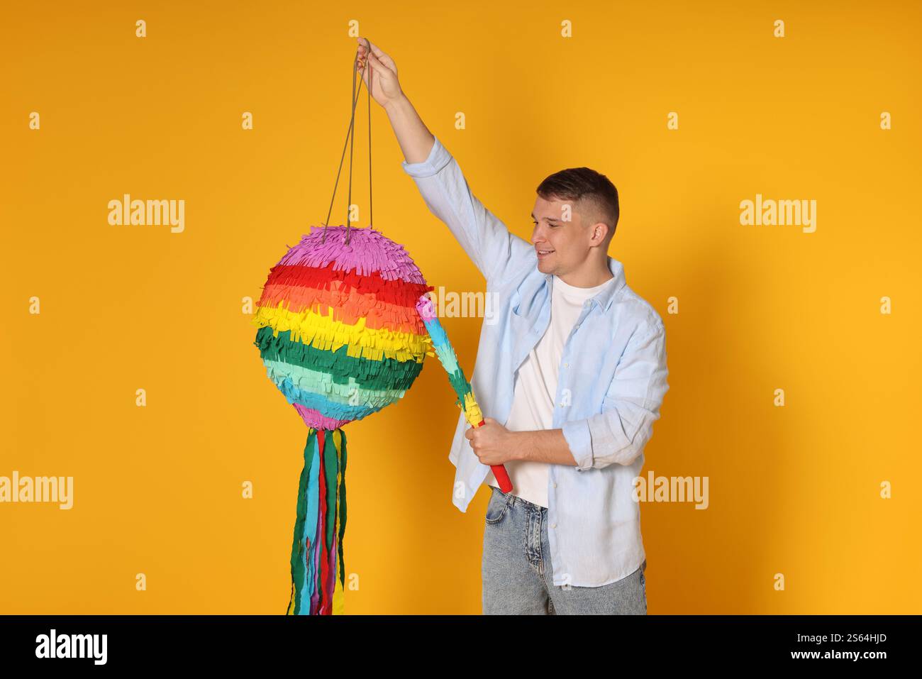 Happy man breaking pinata on yellow background Stock Photo - Alamy