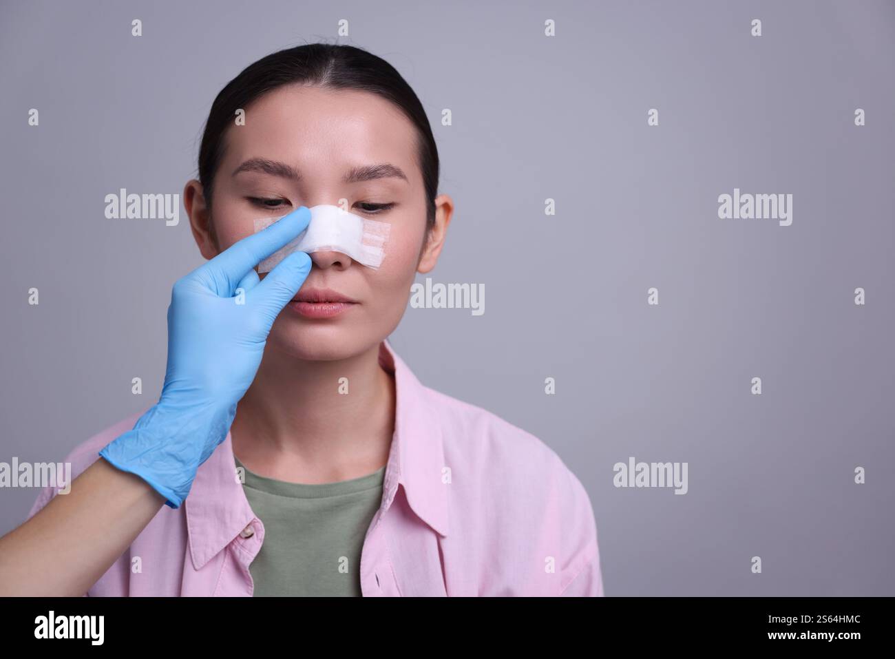 Doctor checking patient's nose after plastic surgery operation on light ...