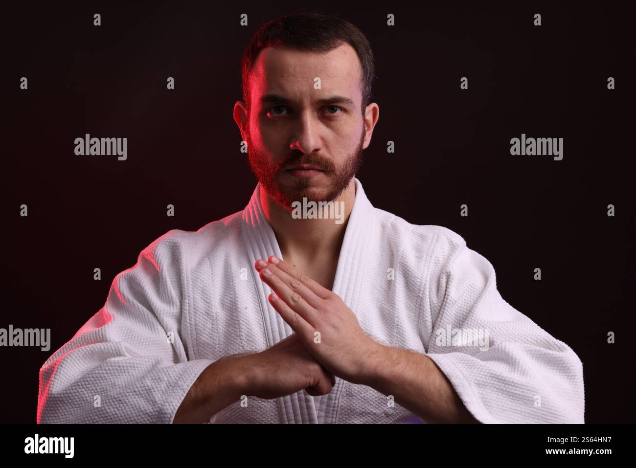 Karate fighter wearing uniform in color light against black background ...
