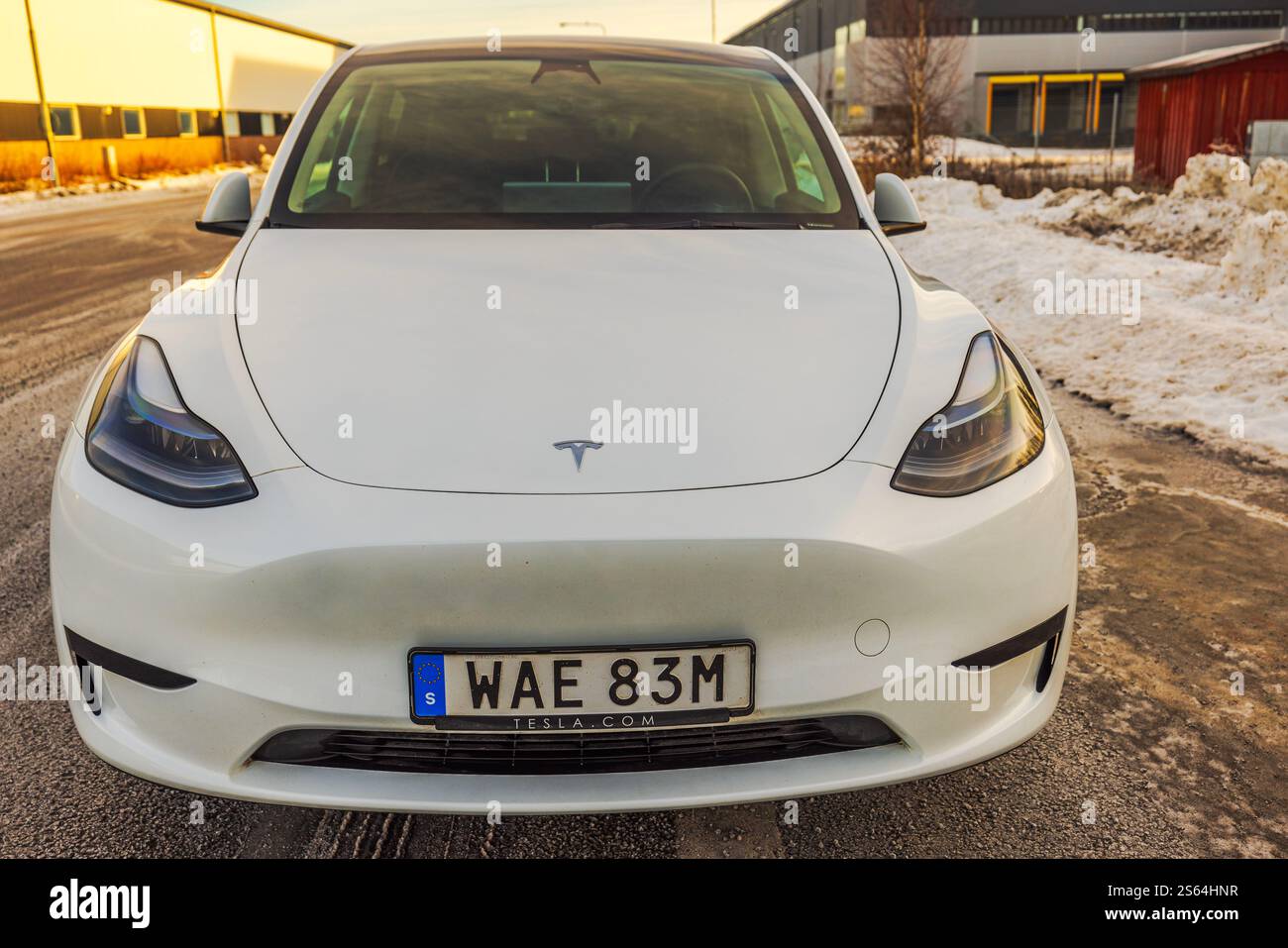 Front view of white Tesla Model Y parked on snowy road near industrial ...