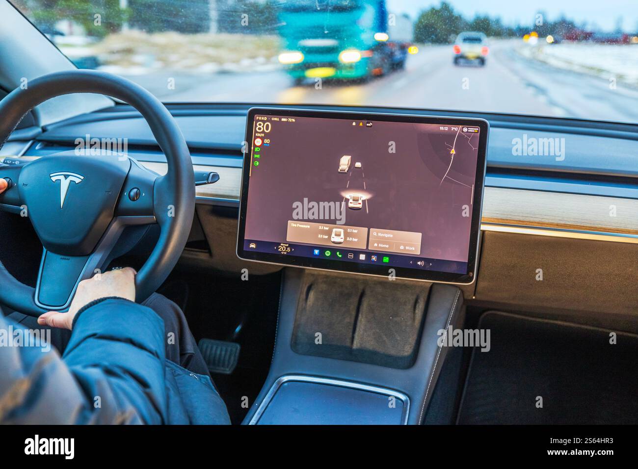 Woman driving Tesla Model Y on a winter road with touchscreen showing ...