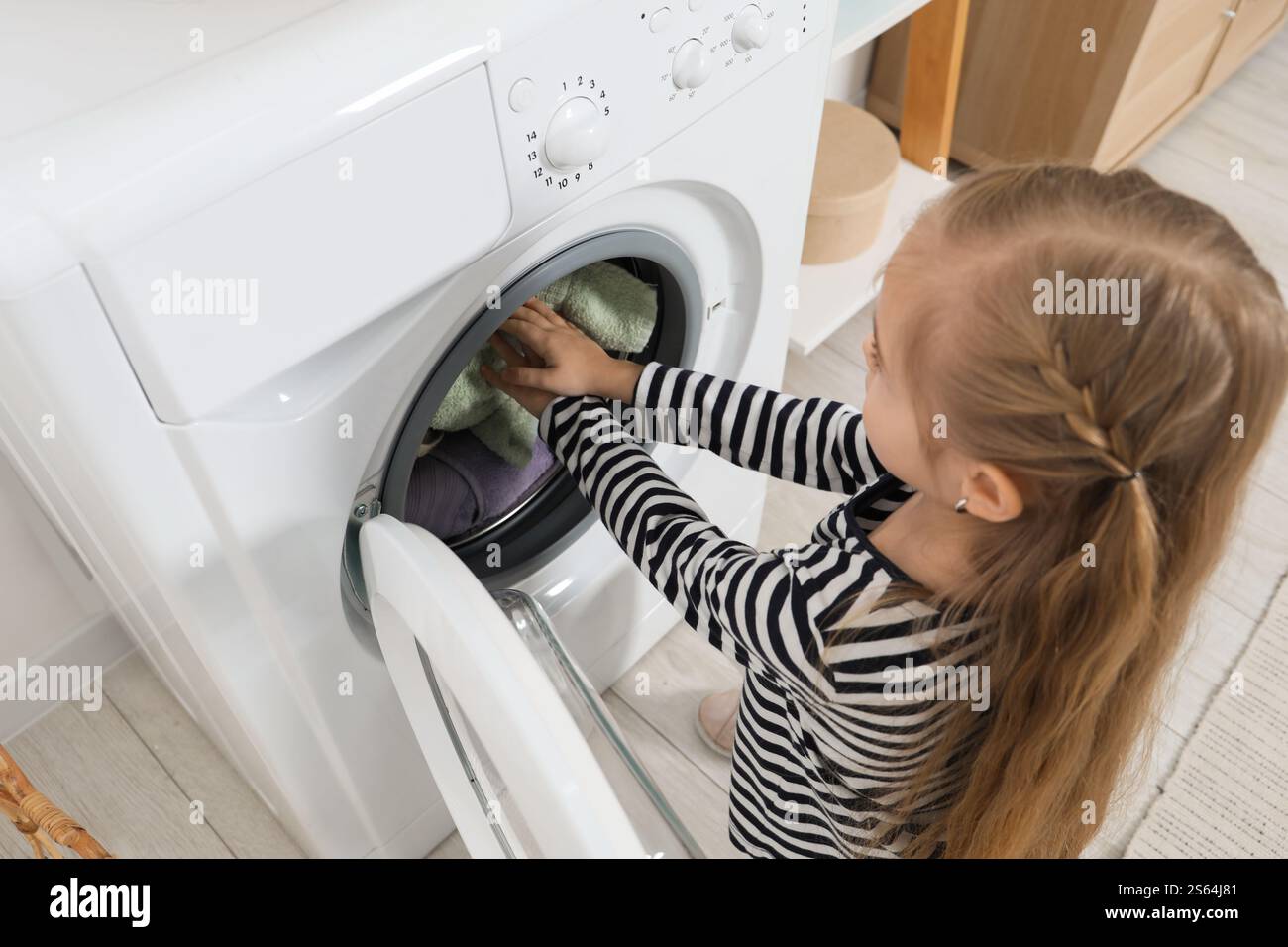 Little helper. Cute girl doing laundry at home, above view Stock Photo ...