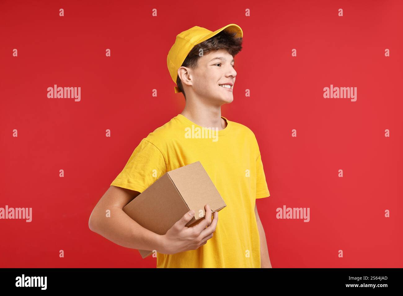 Teenage boy with parcel working as courier on red background Stock ...