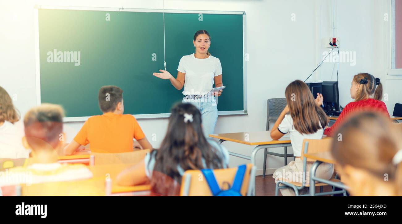 Teacher reading lecture to schoolkids in classroom Stock Photo - Alamy