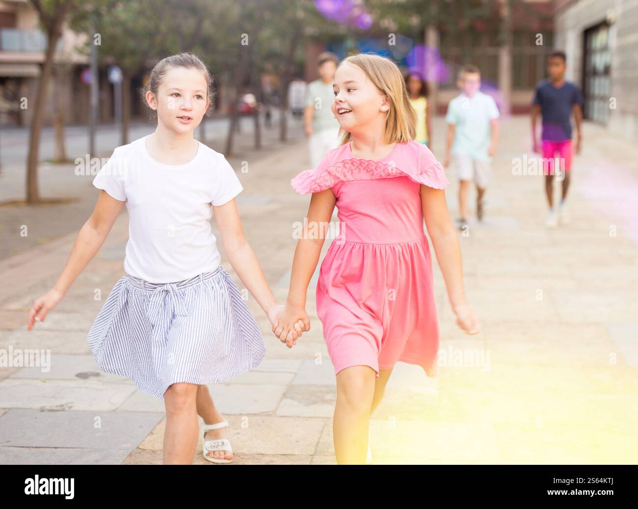 Two cheerful preteen girls enjoying walk along city street Stock Photo ...