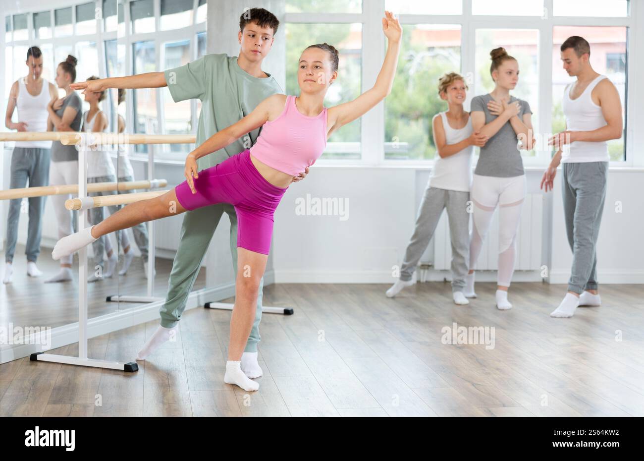 Teenage girl and boy practicing arabesque position of ballet in dance ...