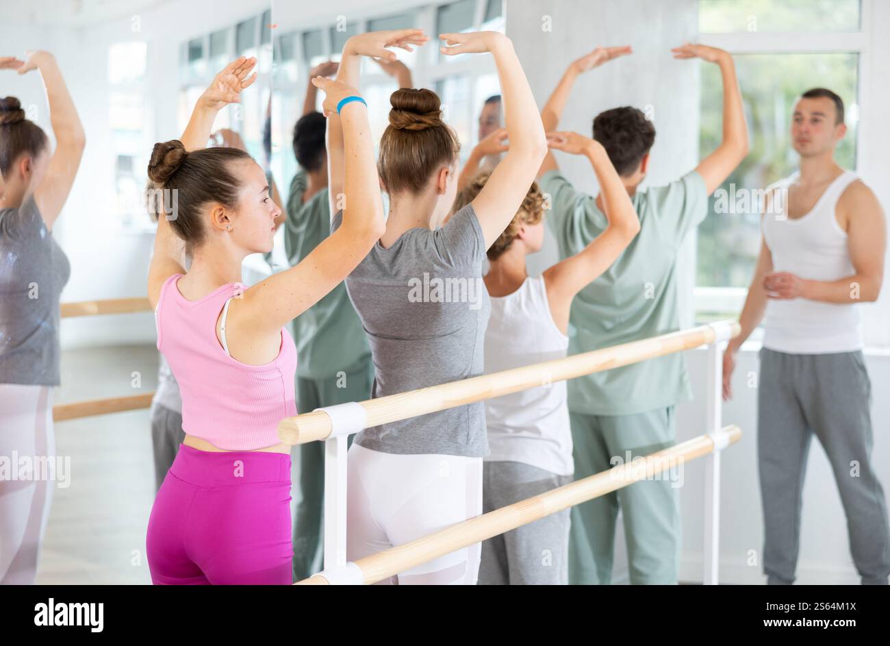 Girls and boys in ballet class perform fifth position under male ...
