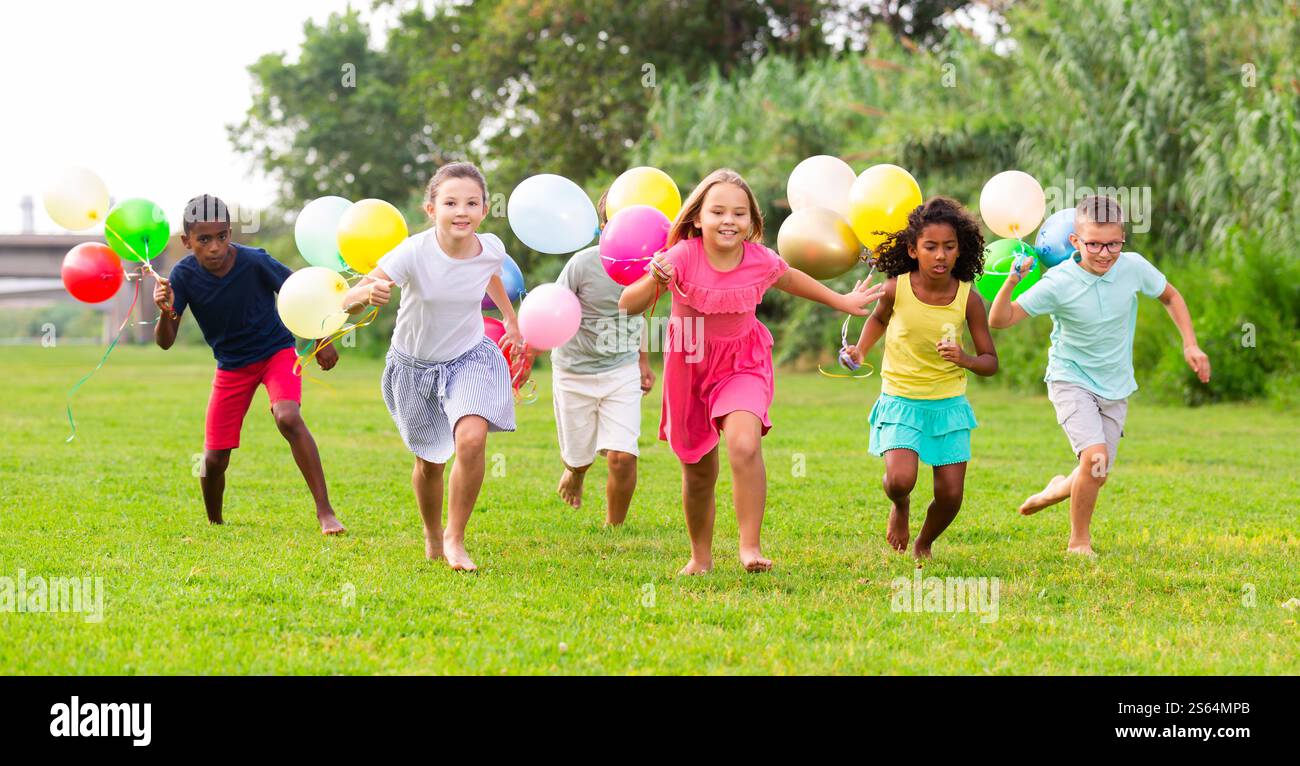 Boys and girls with balloons running thruogh field Stock Photo - Alamy