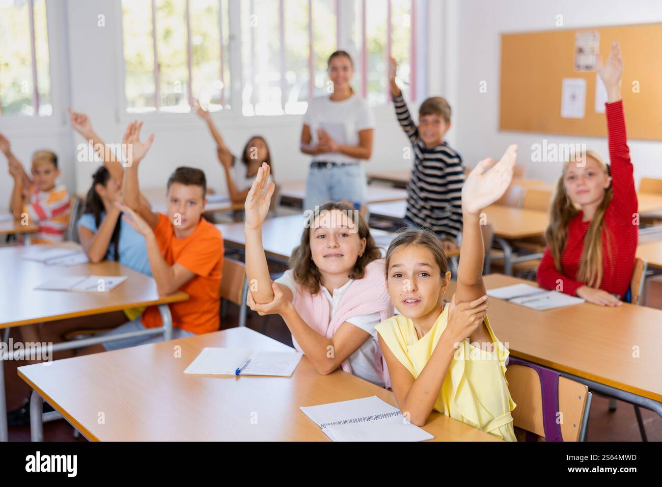 Studious preteen pupils raising hands to answer in class Stock Photo ...