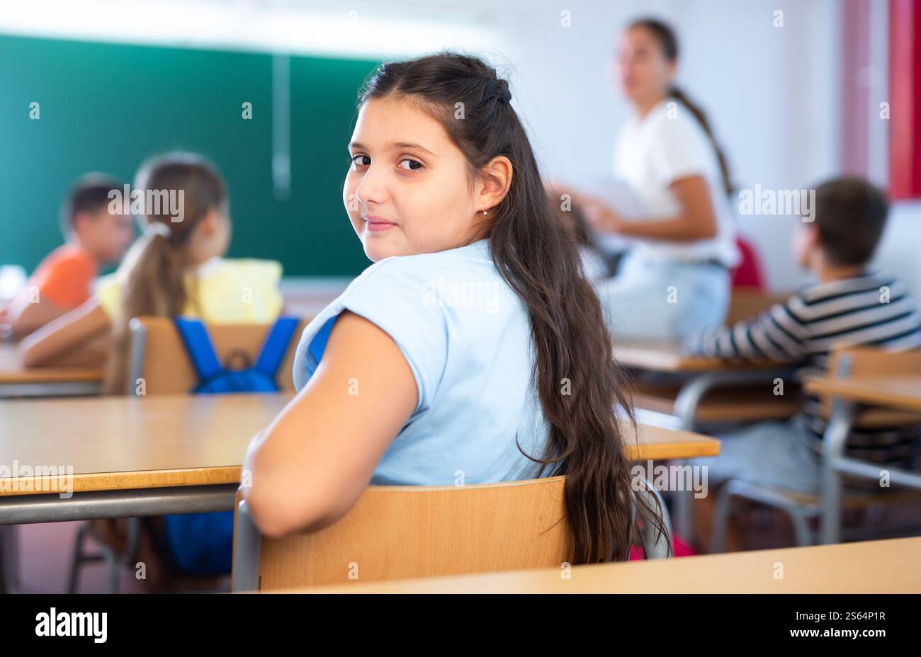 Positive tween schoolgirl sitting at lesson in classroom Stock Photo ...