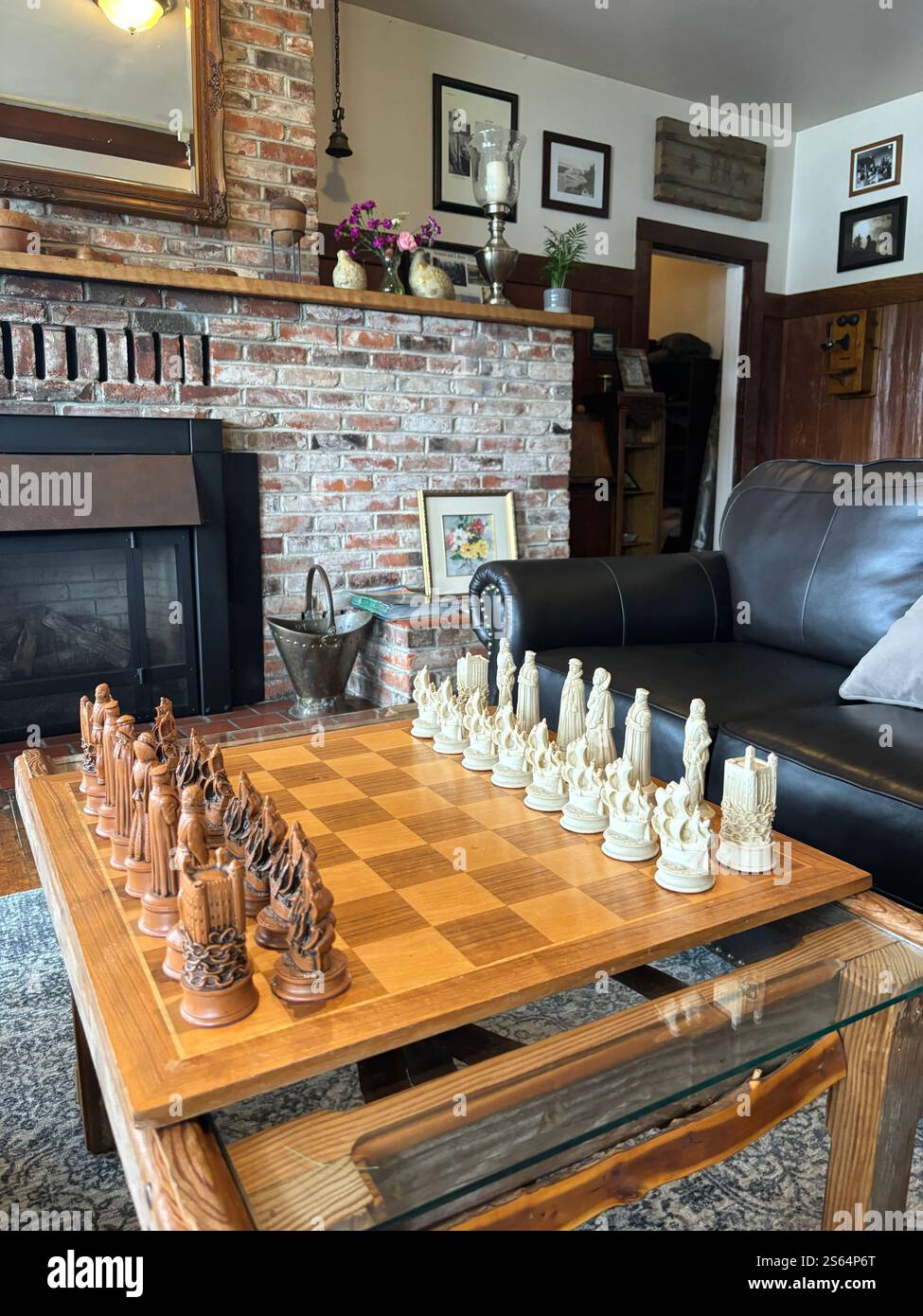 Chess set on a chess board in front of a dark leather couch and a brick ...