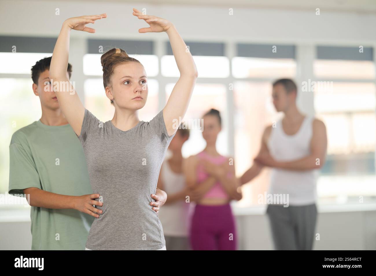 Teenage girl practicing ballet positions in pair with boy in dance ...