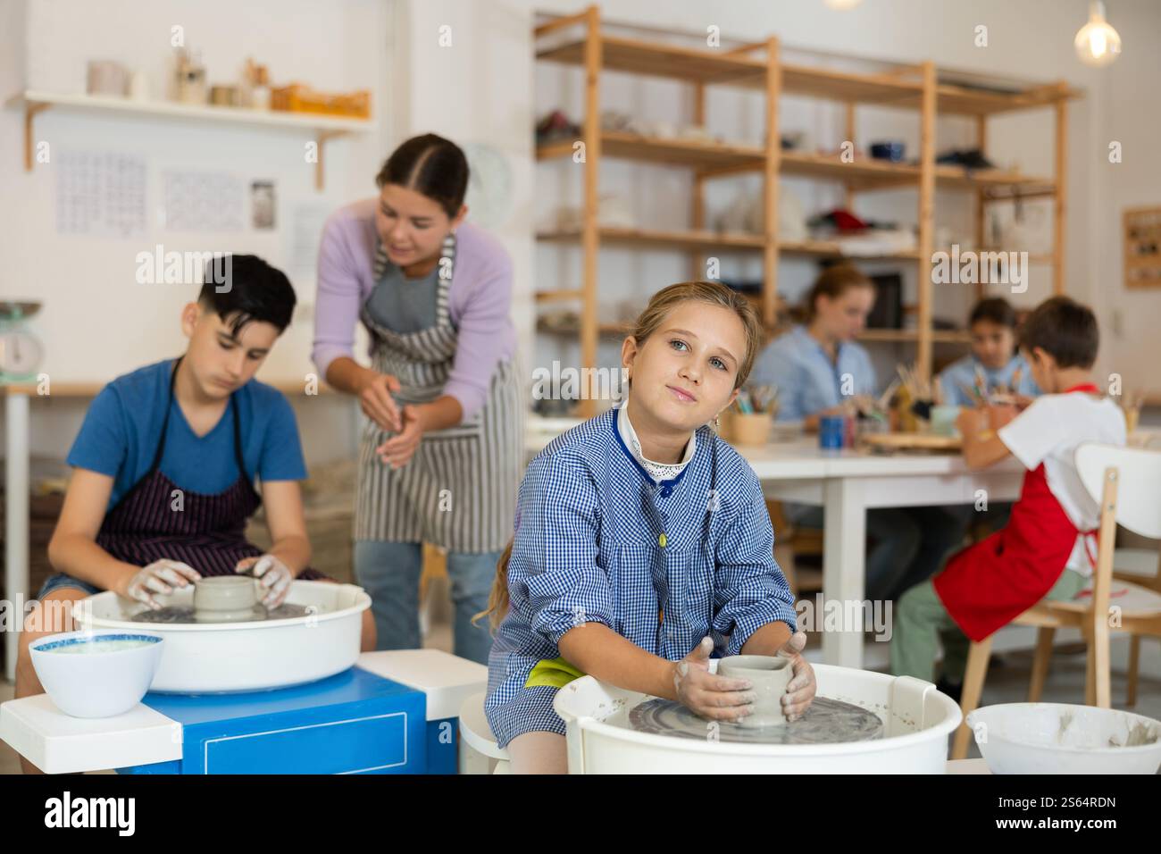 Children working at potter's wheel with teacher in art studio Stock ...