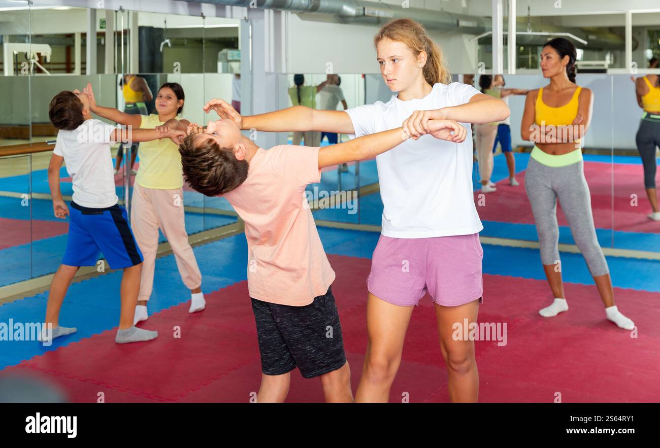 Kids in pair exercising self-defense movements during group class with ...
