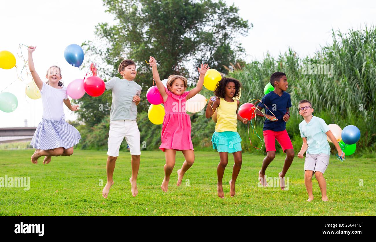 Boys and girls with balloons jumping on lawn Stock Photo - Alamy