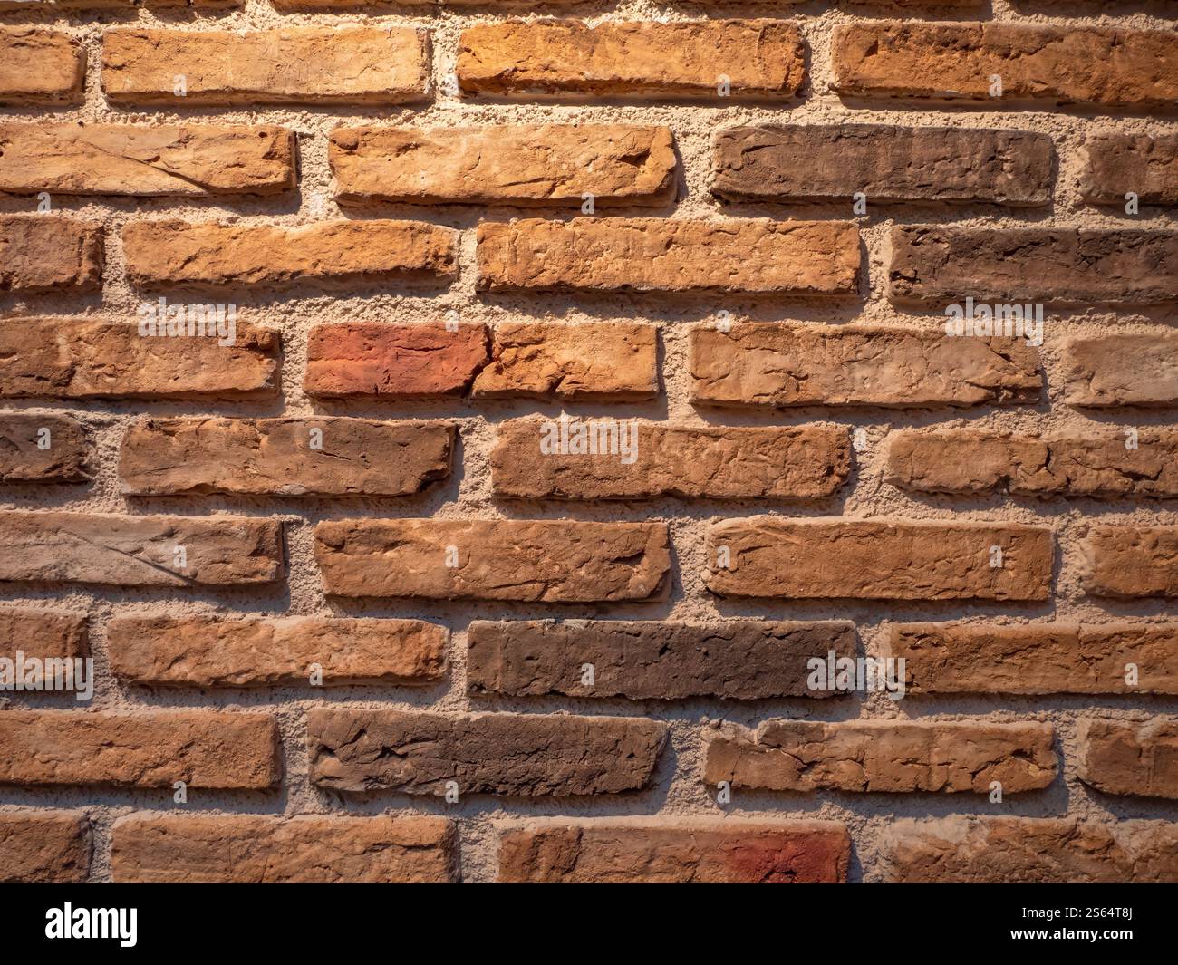 Close-up of a textured brick wall with warm tones, showing rough and ...