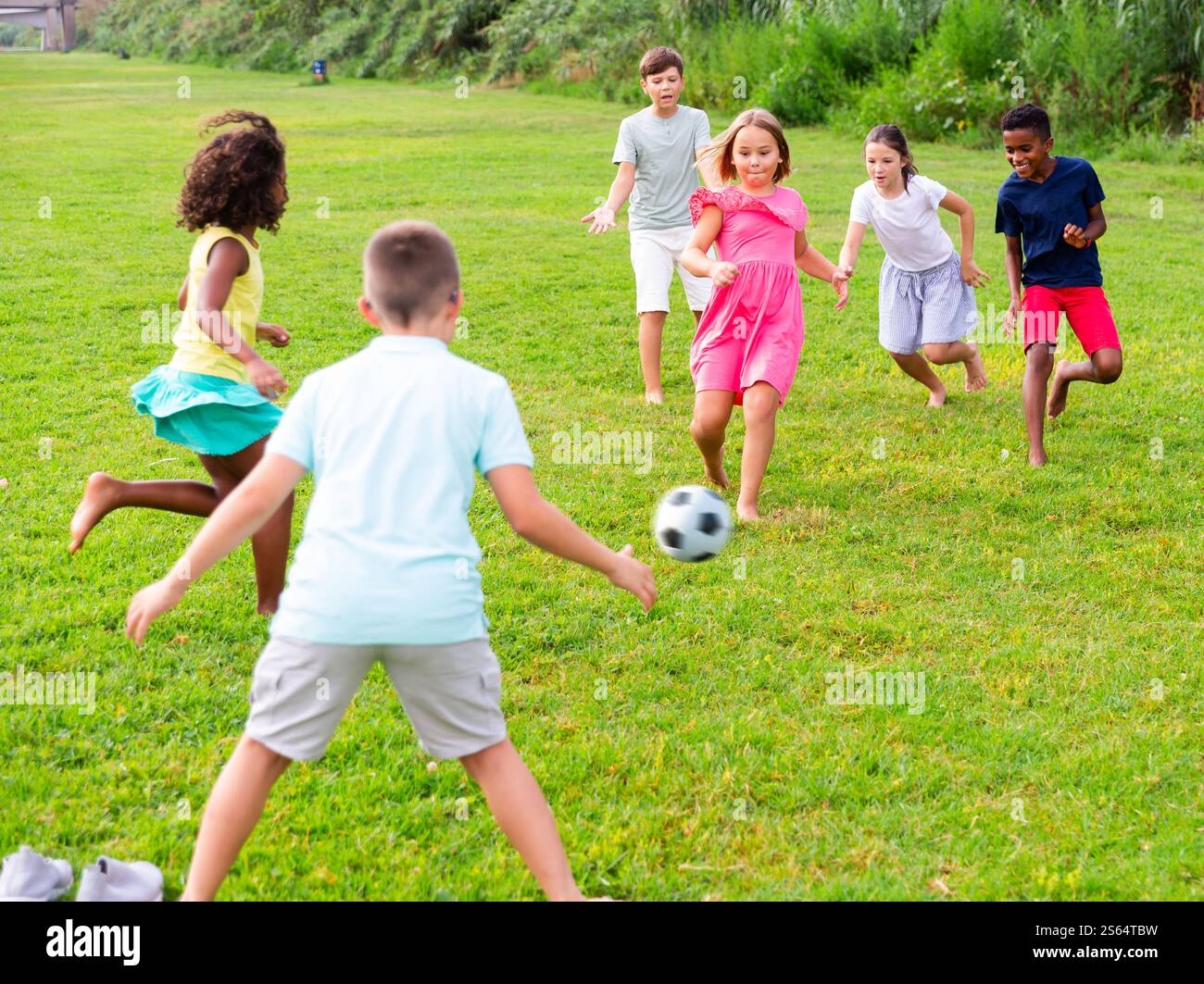 Kids running through grass and playing football Stock Photo - Alamy