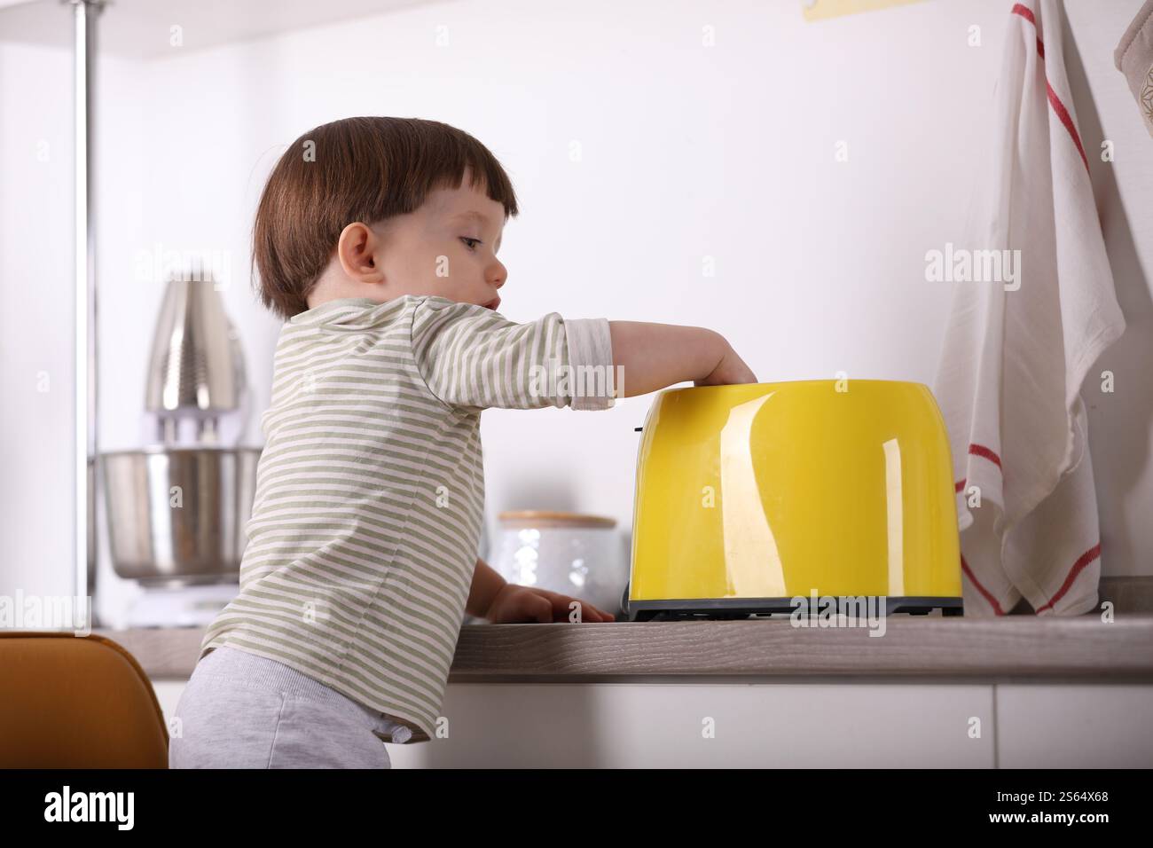 Little boy playing with toaster in kitchen. Dangerous situation Stock ...