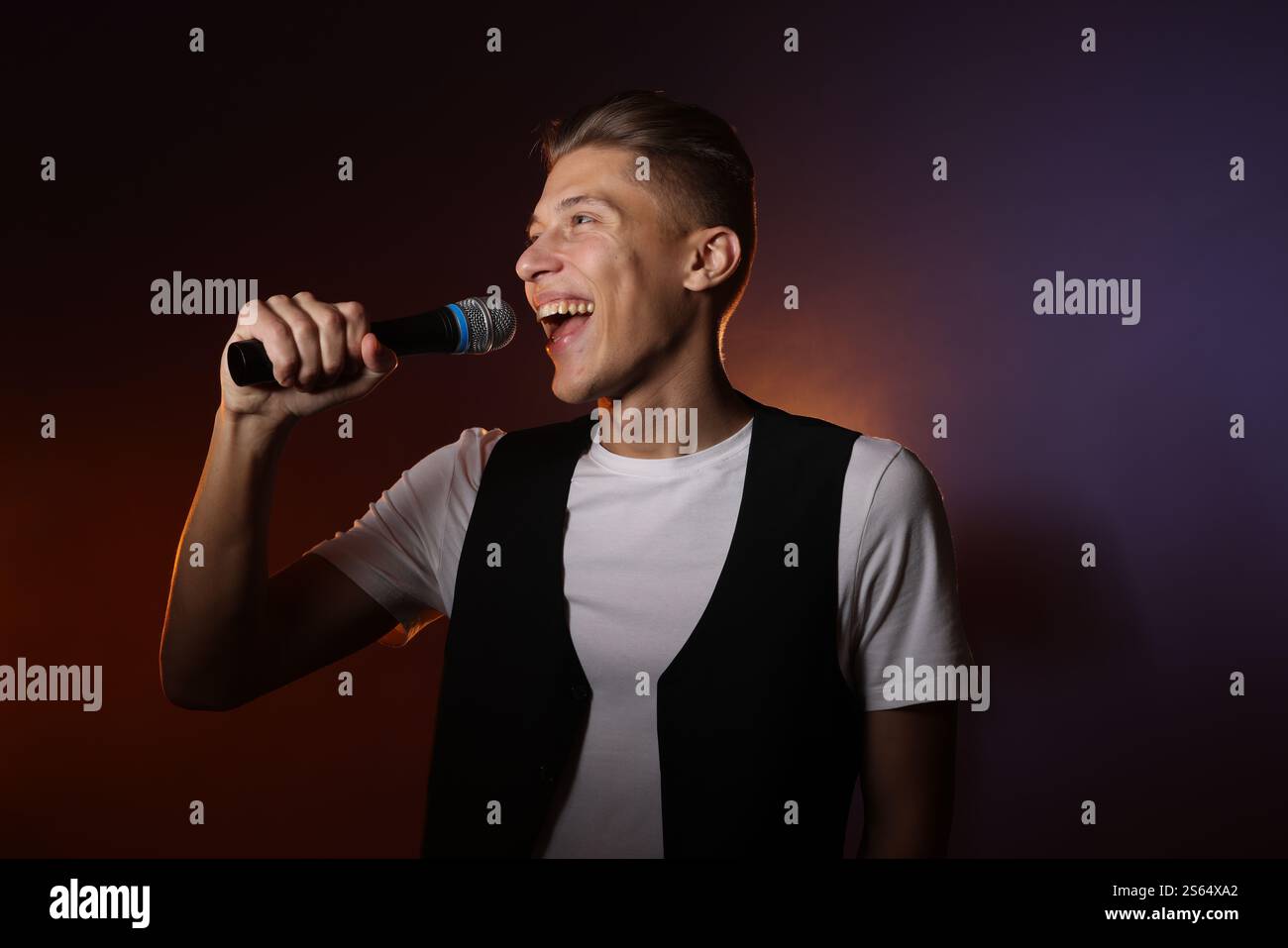 Talented young man singing on dark background with color light Stock ...