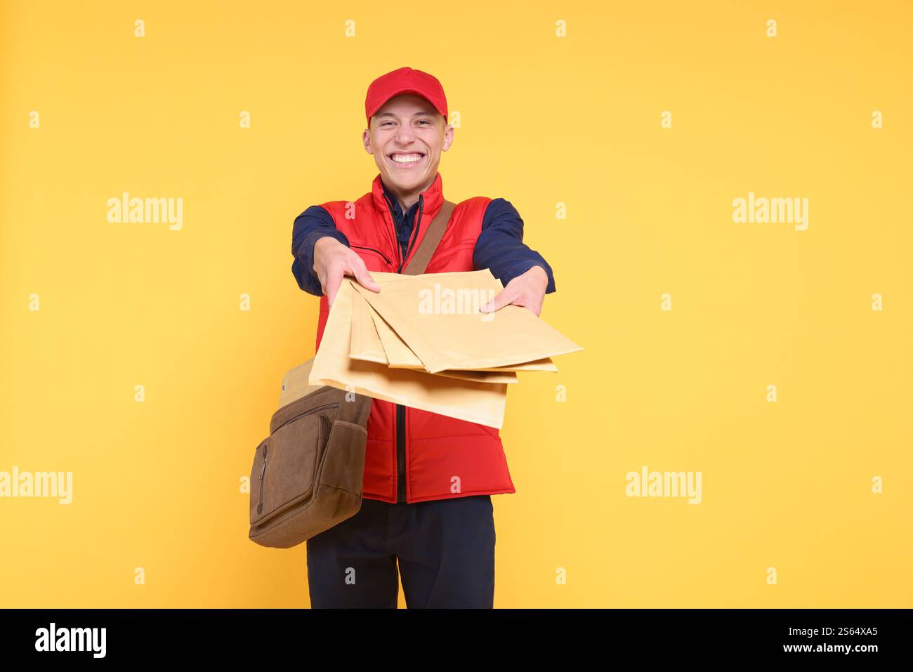 Happy postman with bag giving envelopes on yellow background Stock ...