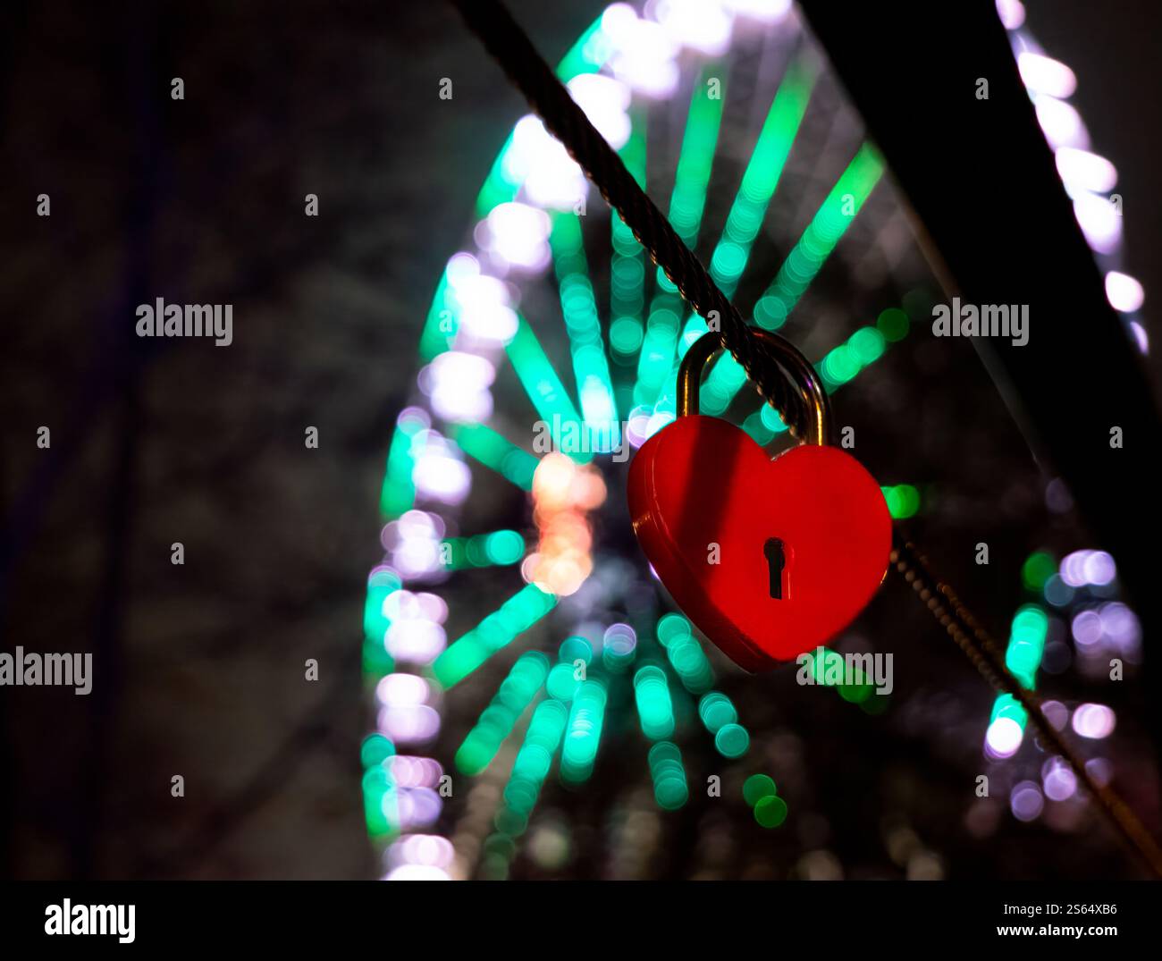 Red heart-shaped love lock attached to a rope with a Ferris wheel ...