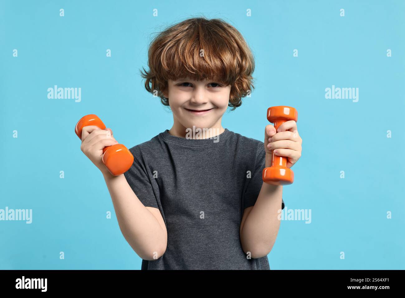 Little boy with dumbbells on light blue background Stock Photo - Alamy