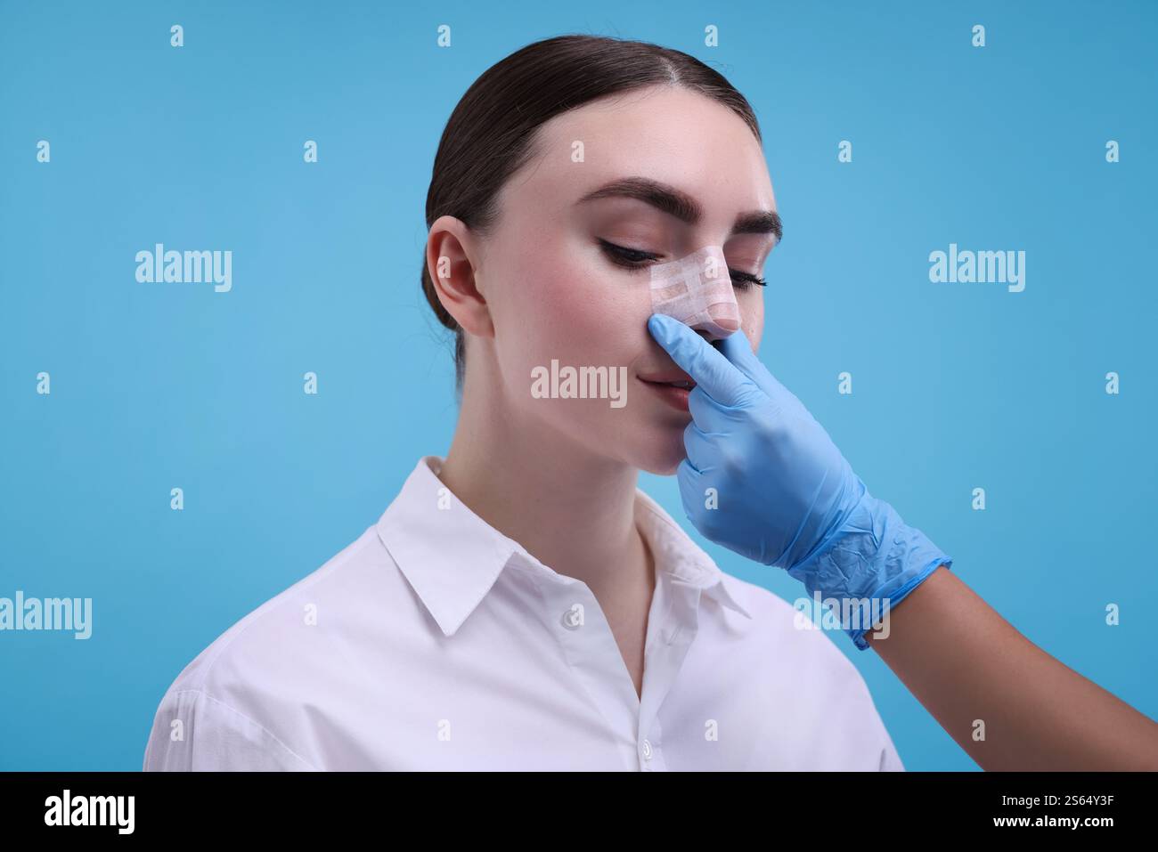 Doctor checking patient's nose after plastic surgery operation on light ...