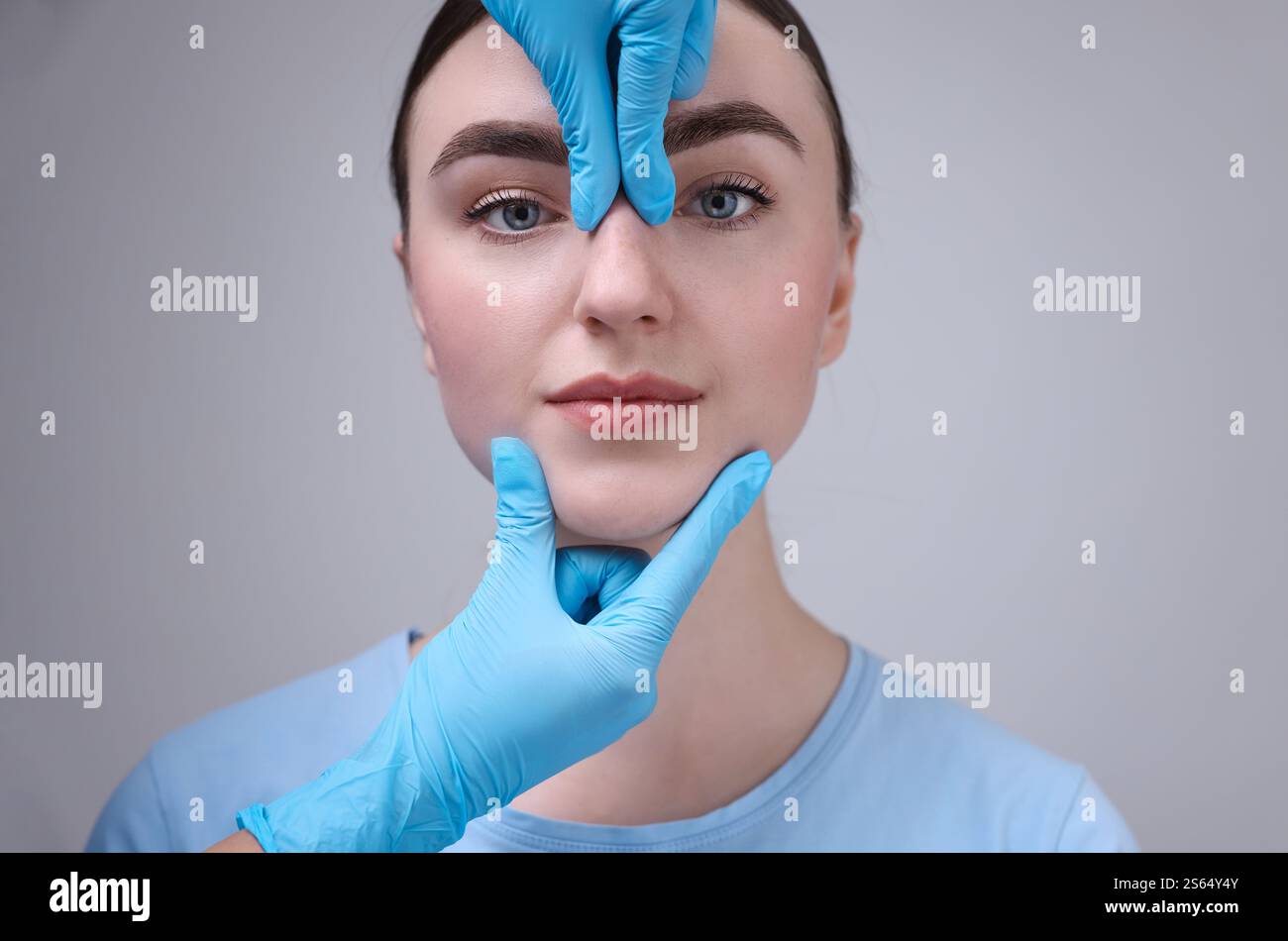Doctor checking patient's nose before plastic surgery operation on grey ...