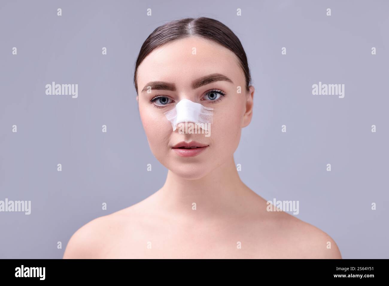 Woman with medical bandage on her nose after plastic surgery operation ...