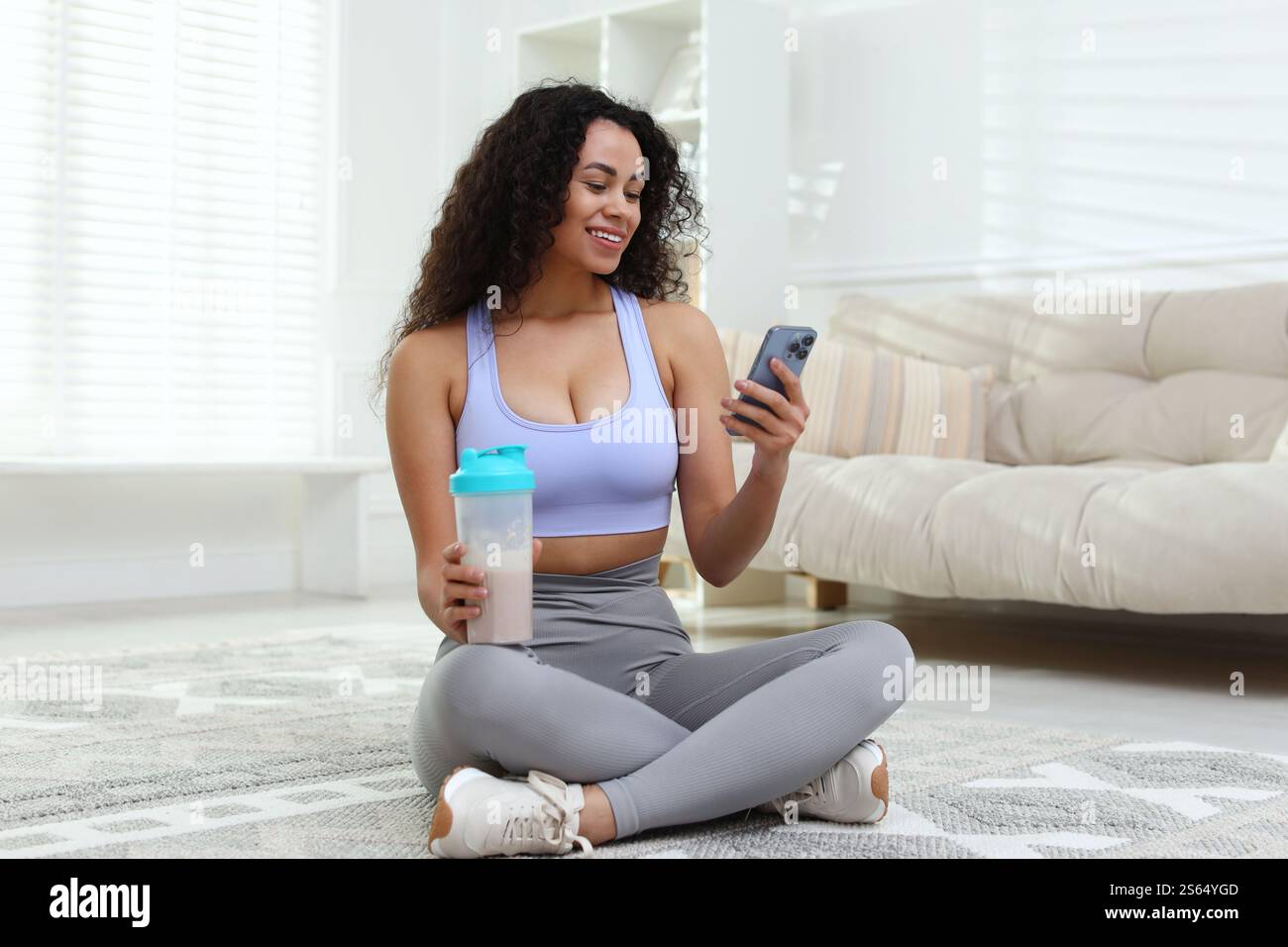 Beautiful woman with protein shake and smartphone at home Stock Photo ...