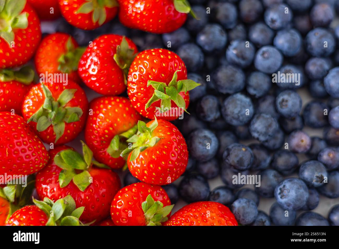 Top view of freshly picked strawberries and blueberries side by side ...