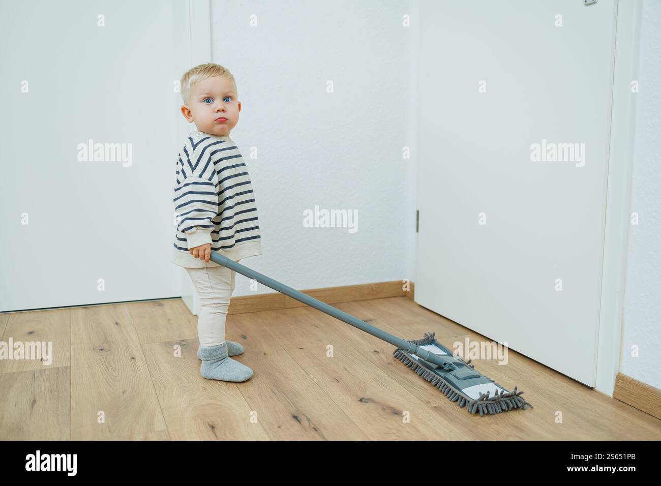Child boy cleaning the floor at home. Boy washes the floor with a mop ...