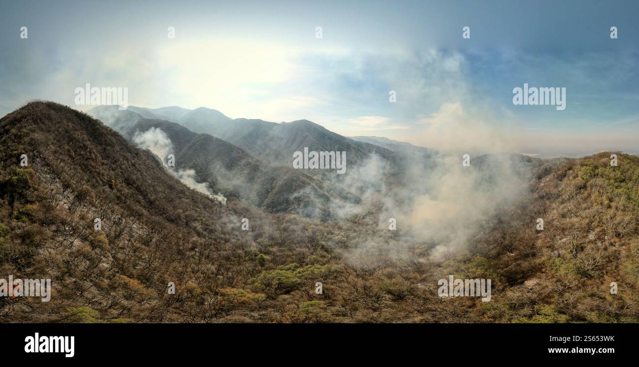 Aerial view of a wildfire spreading across mountainous terrain, with ...