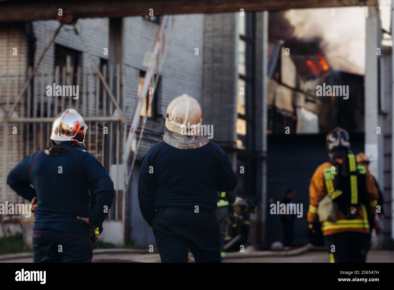 Group of fire men in uniform during fire fighting operation in the city ...