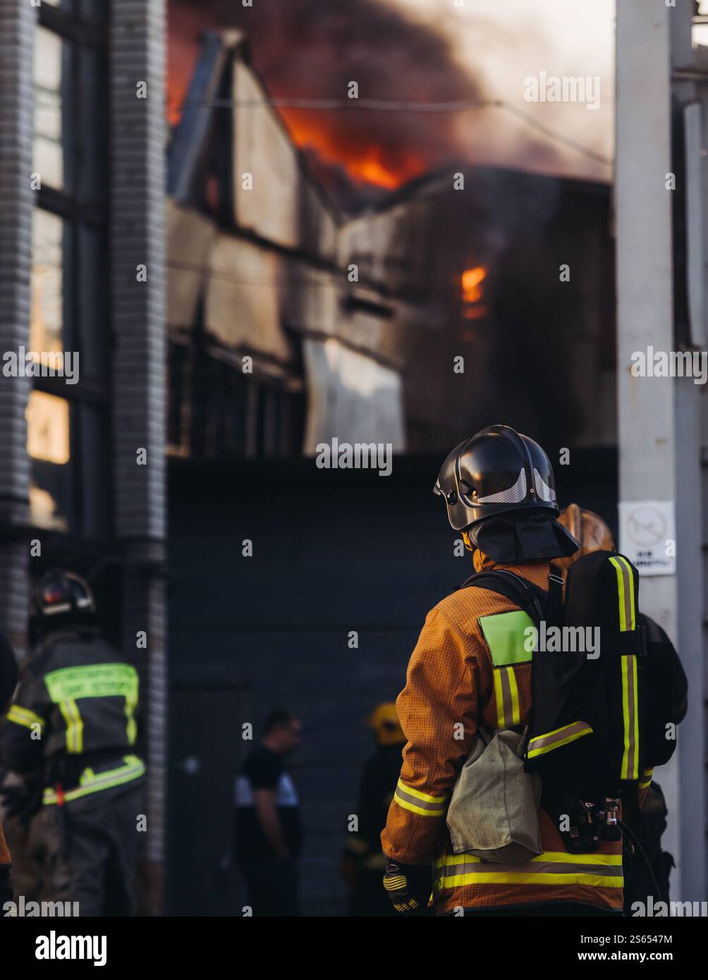 Group of fire men in uniform during fire fighting operation in the city ...