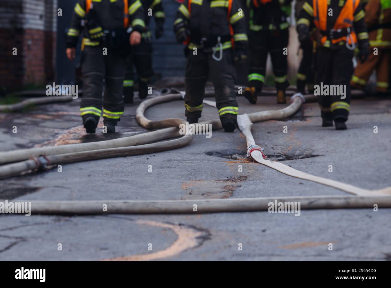 Group of fire men in uniform during fire fighting operation in the city ...