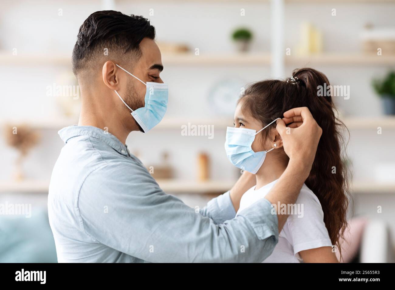Middle-eastern man putting face mask on her daughter Stock Photo - Alamy