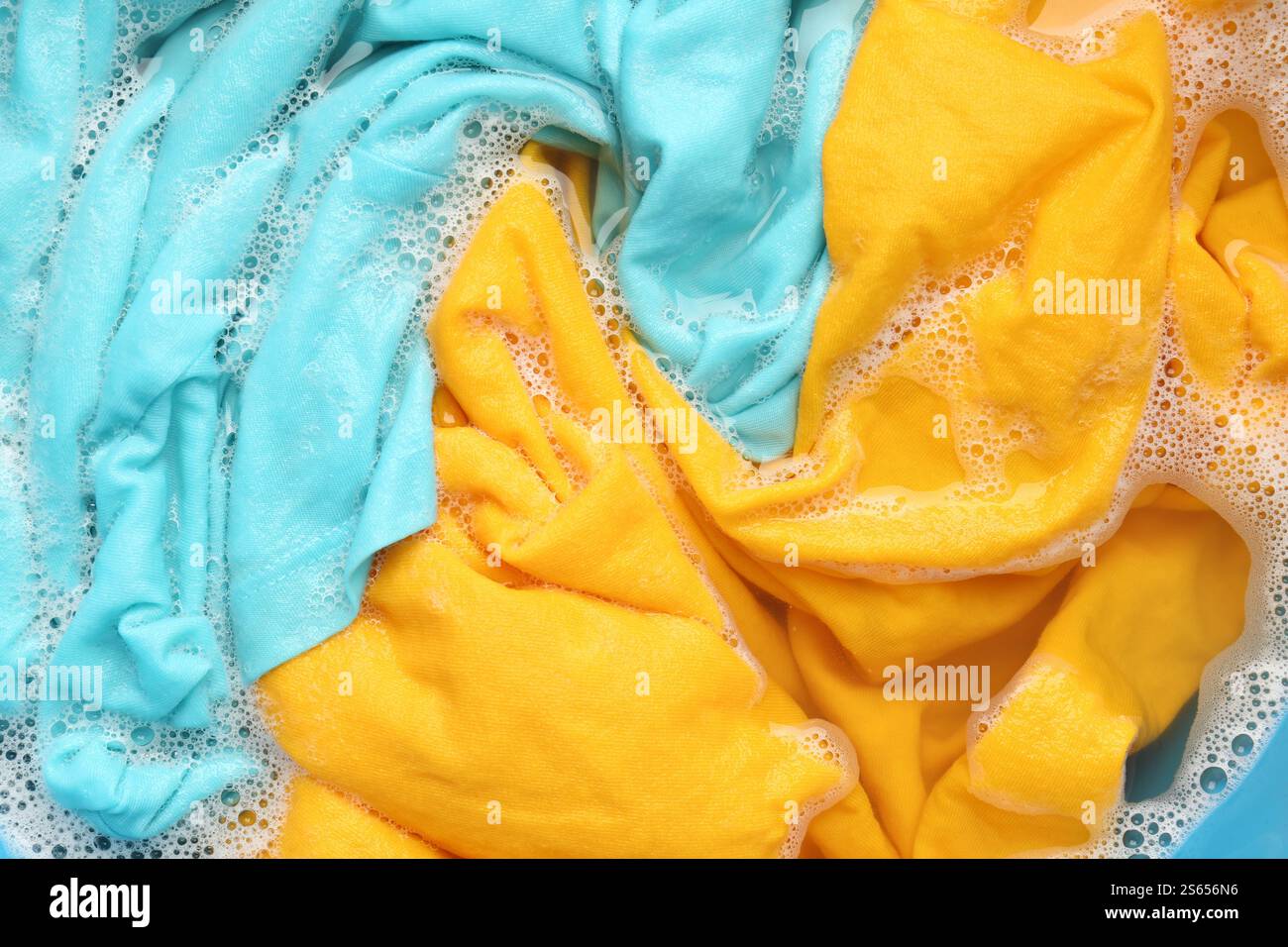 Colorful clothes soaked in water before washing, top view Stock Photo ...