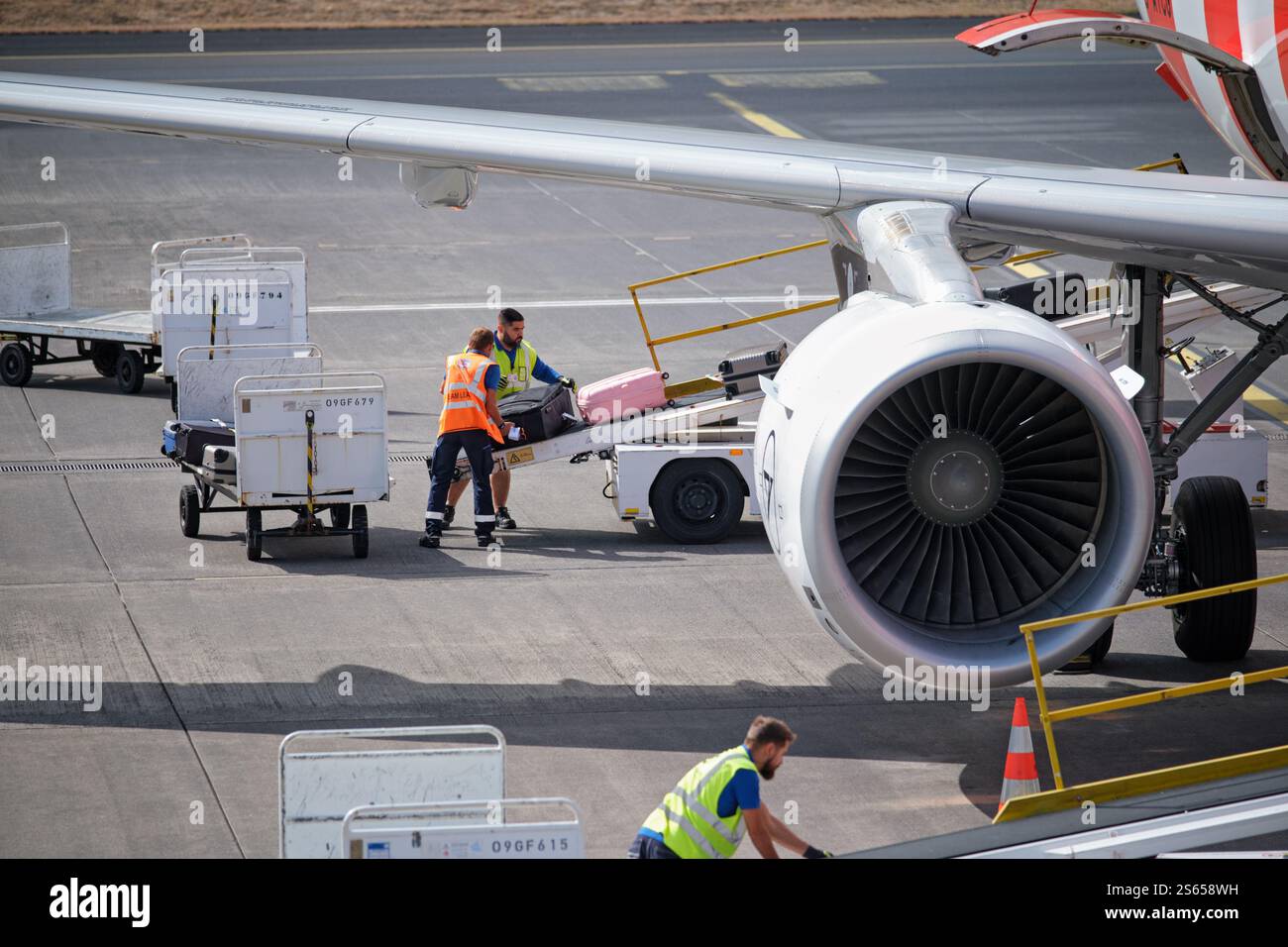 Airport ground crew man is loading luggage suitcases onto a plane from ...